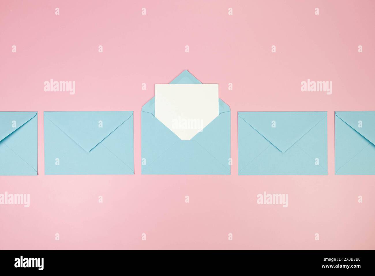 Top view of light blue envelopes, white card on pink background. Post ...