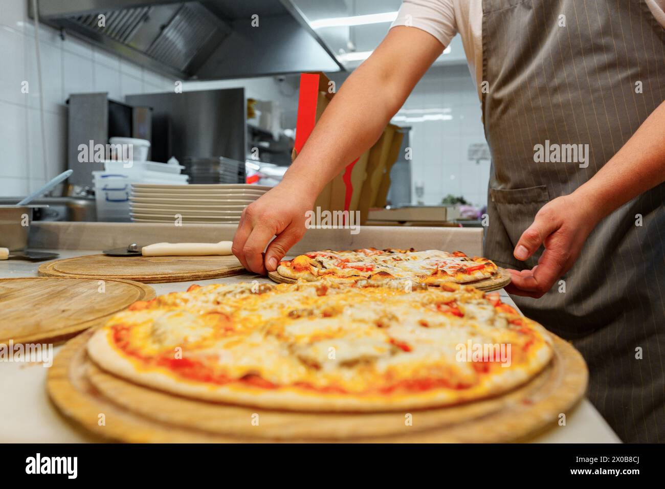 Chef Cutting Freshly Baked Pizza in a Commercial Kitchen Setting Stock ...