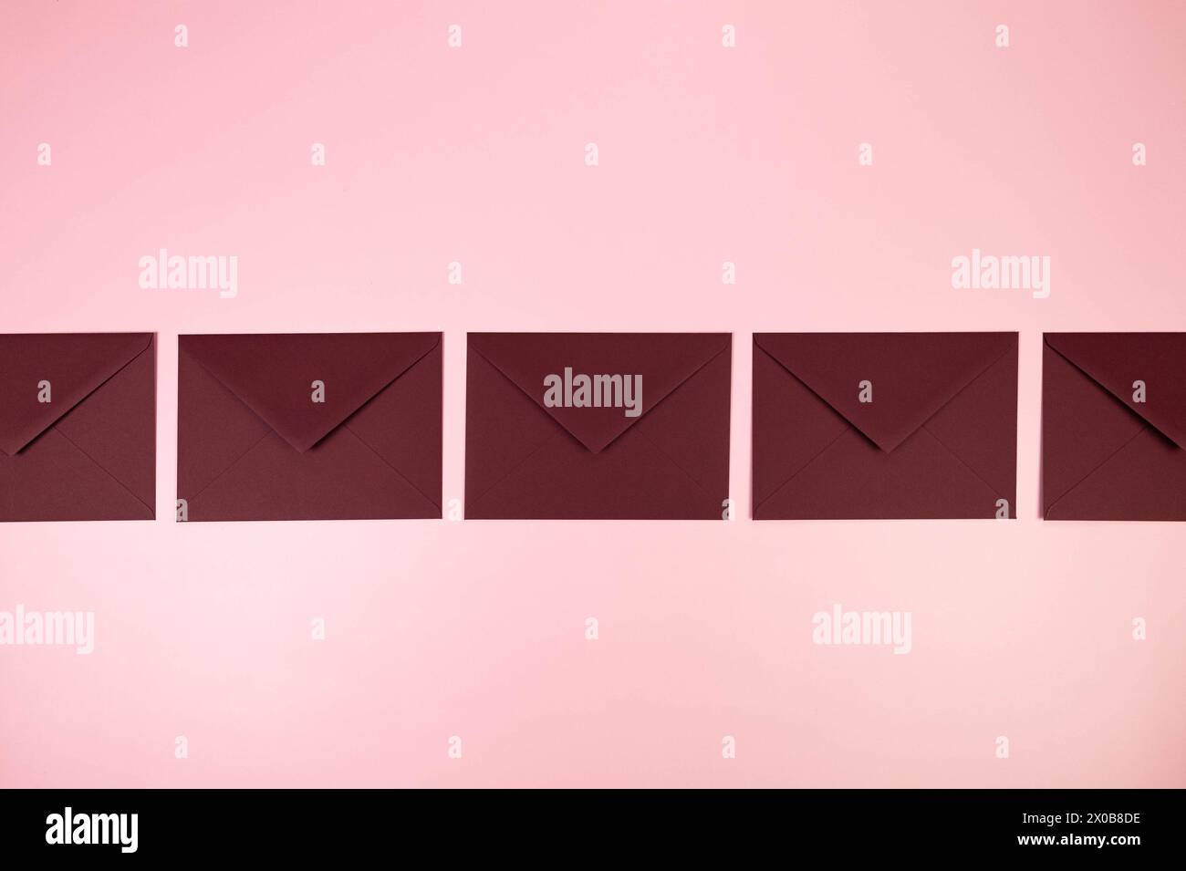 Top view of dark red envelopes on pink background. Post flat lay. Copy ...