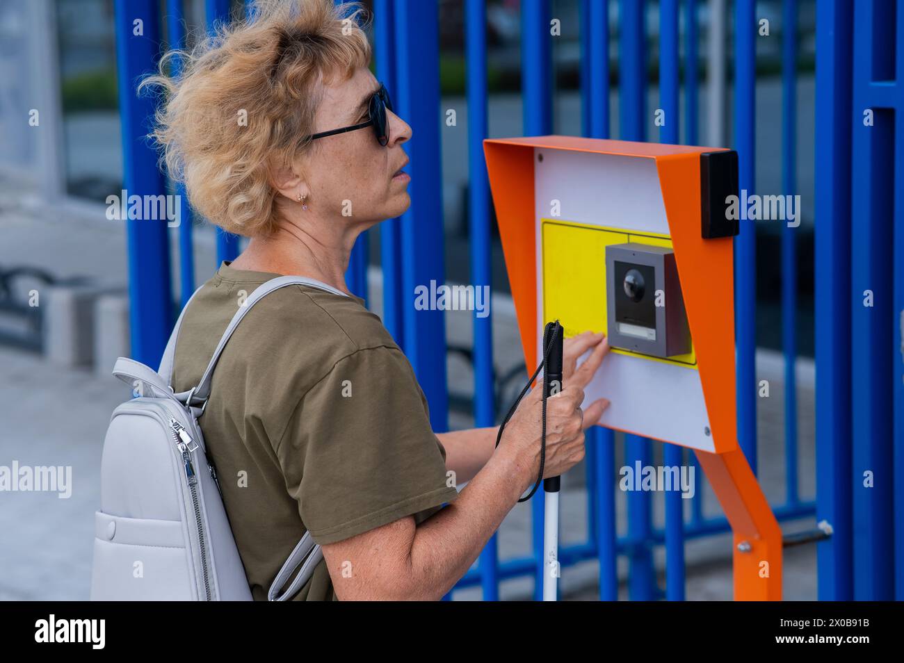 An elderly blind woman reading a text in braille. Button for calling ...
