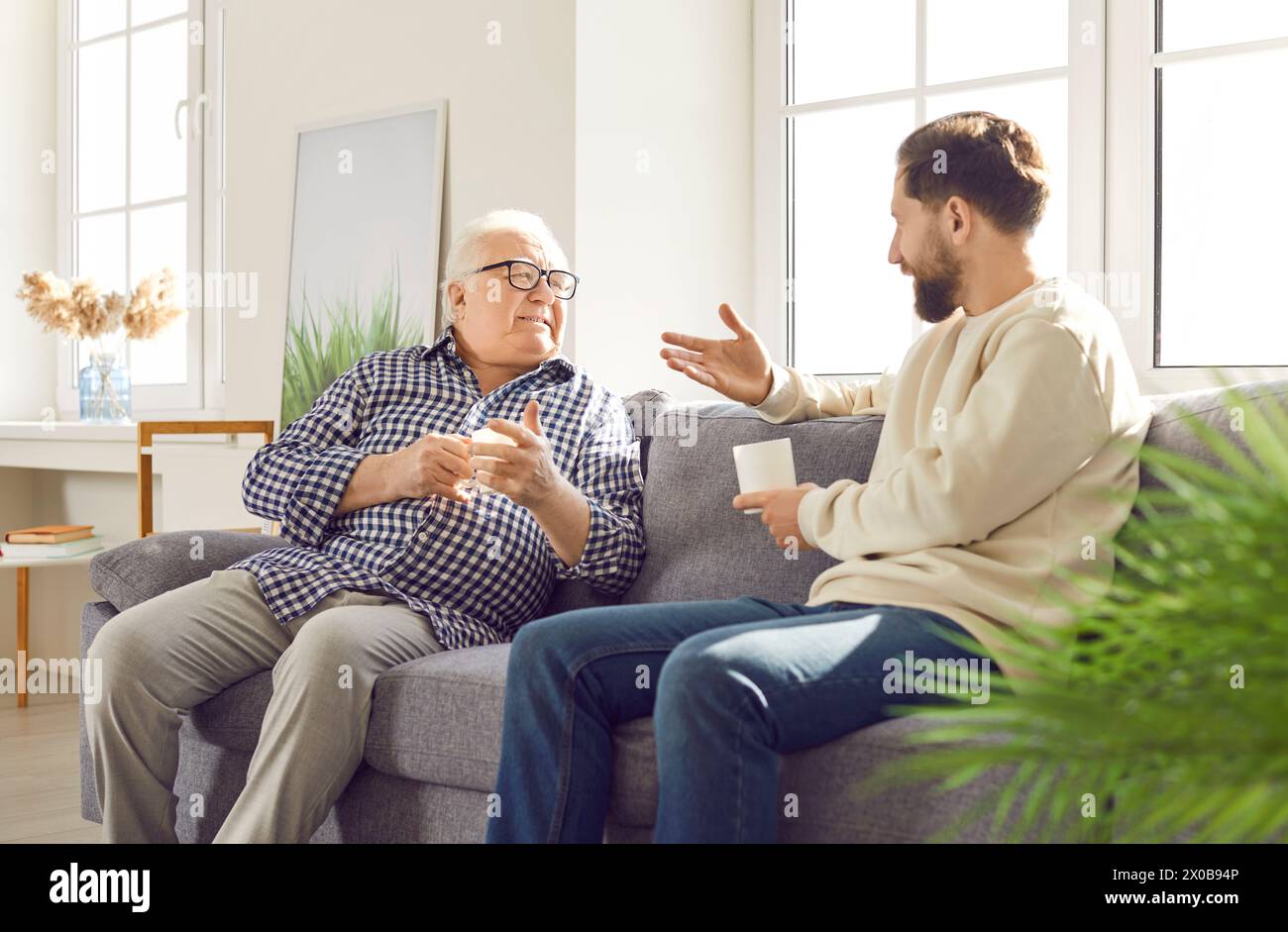 Familial connection family old father adult son sitting on sofa talking ...