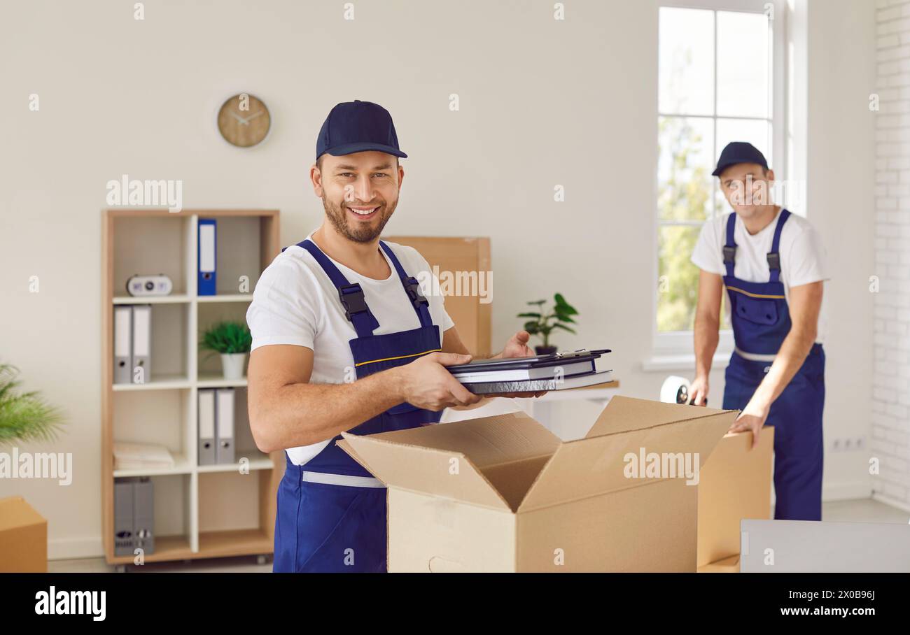 Two professional friendly movers from cardboard boxes unpacking office ...
