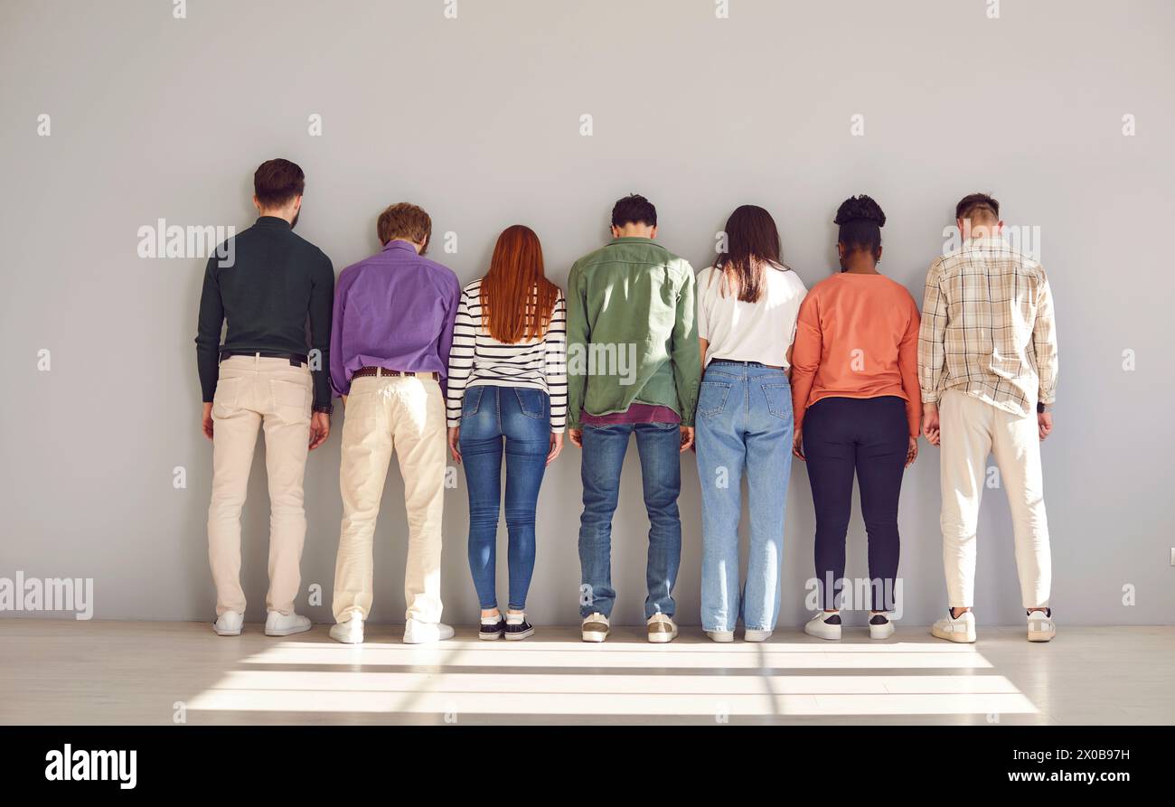 Diverse, silent group of seven people stand in row side by side facing ...