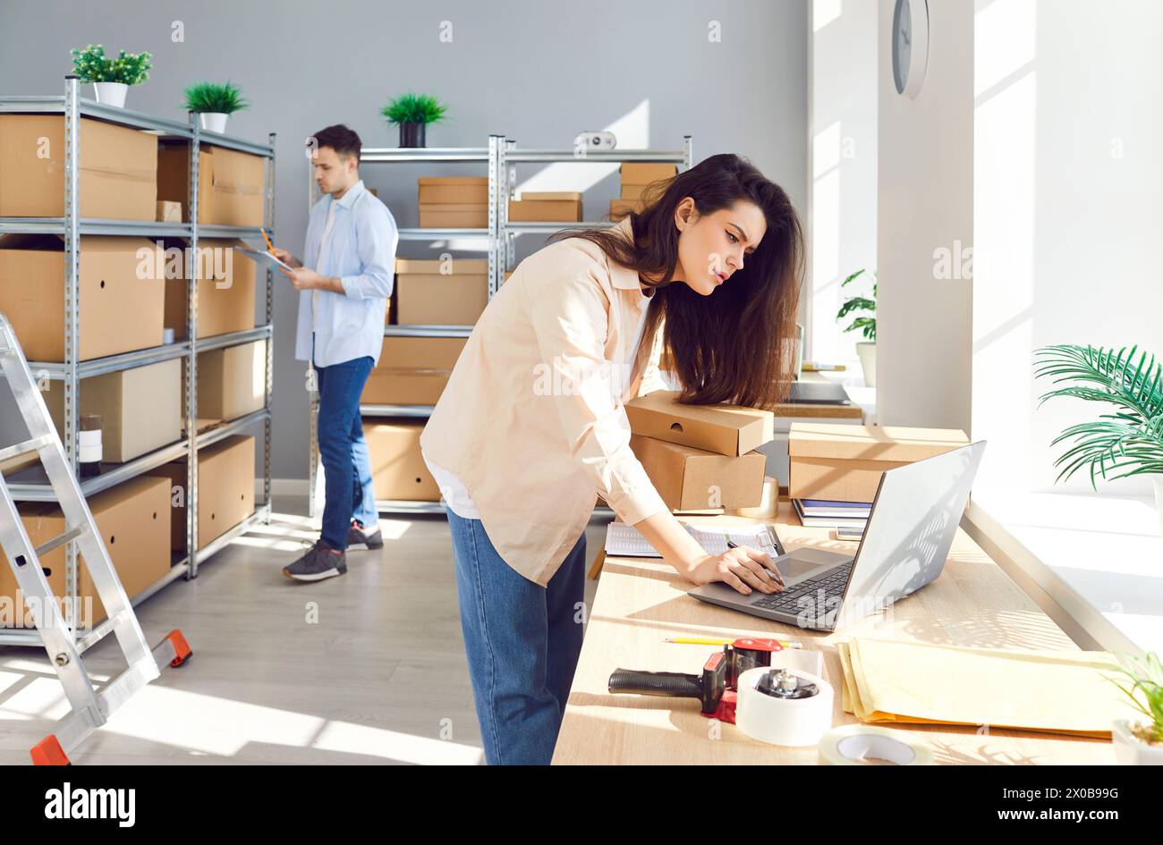 Woman working in logistics center with male colleague preparing order ...
