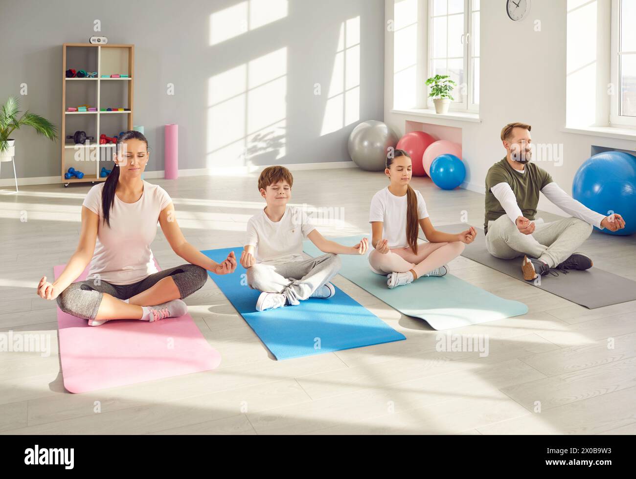 Family yoga lotus pose, happy parents and children learning basic poses ...