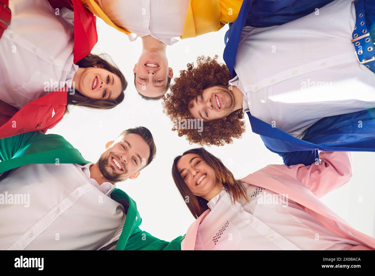Circle of friends huddled together looking down towards camera with ...