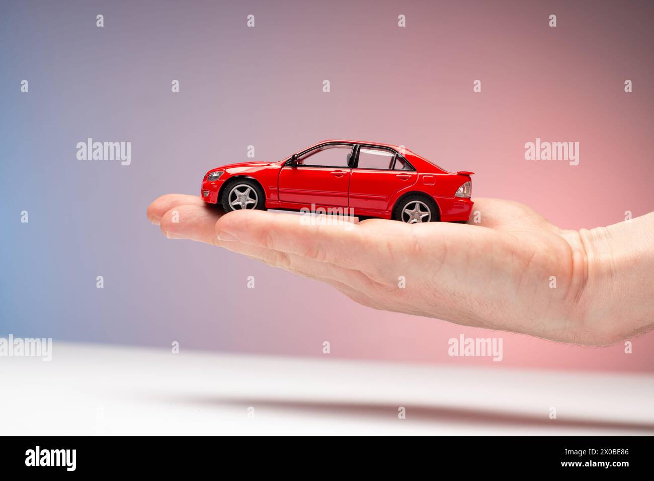 Car insurance. Red toy car on hand. Protect car Stock Photo - Alamy