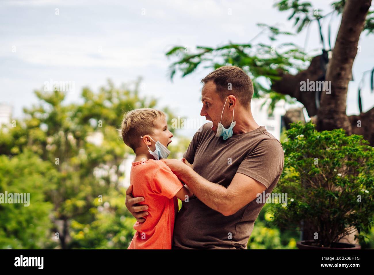 Father and little son hugging, making faces, show a tongue, open mouth ...
