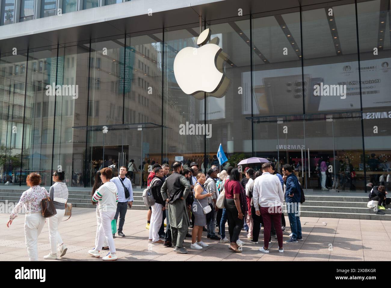 Tourists walk past apple hi-res stock photography and images - Alamy