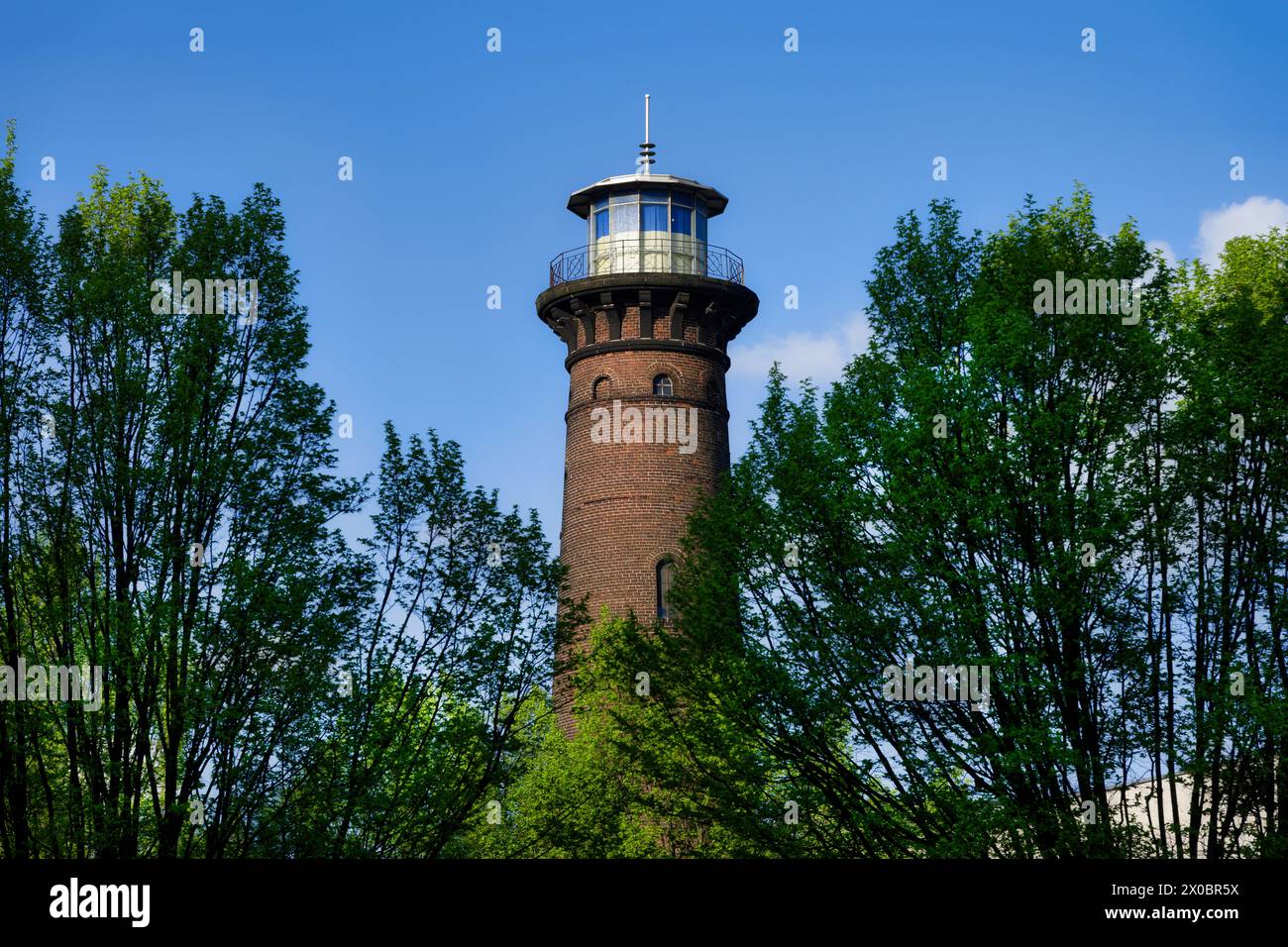 the historic helios lighthouse behind trees and against a blue sky ...
