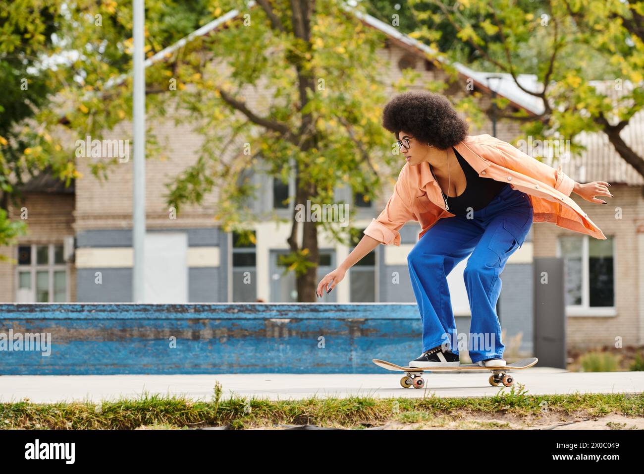 A young African American woman with a skateboard is skateboarding next ...