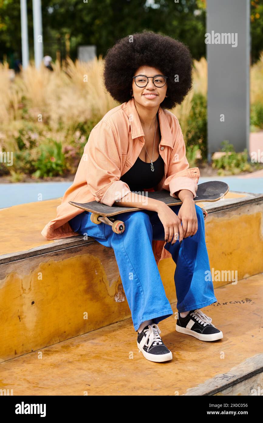 A young African American woman with curly hair sits on a ledge with her ...