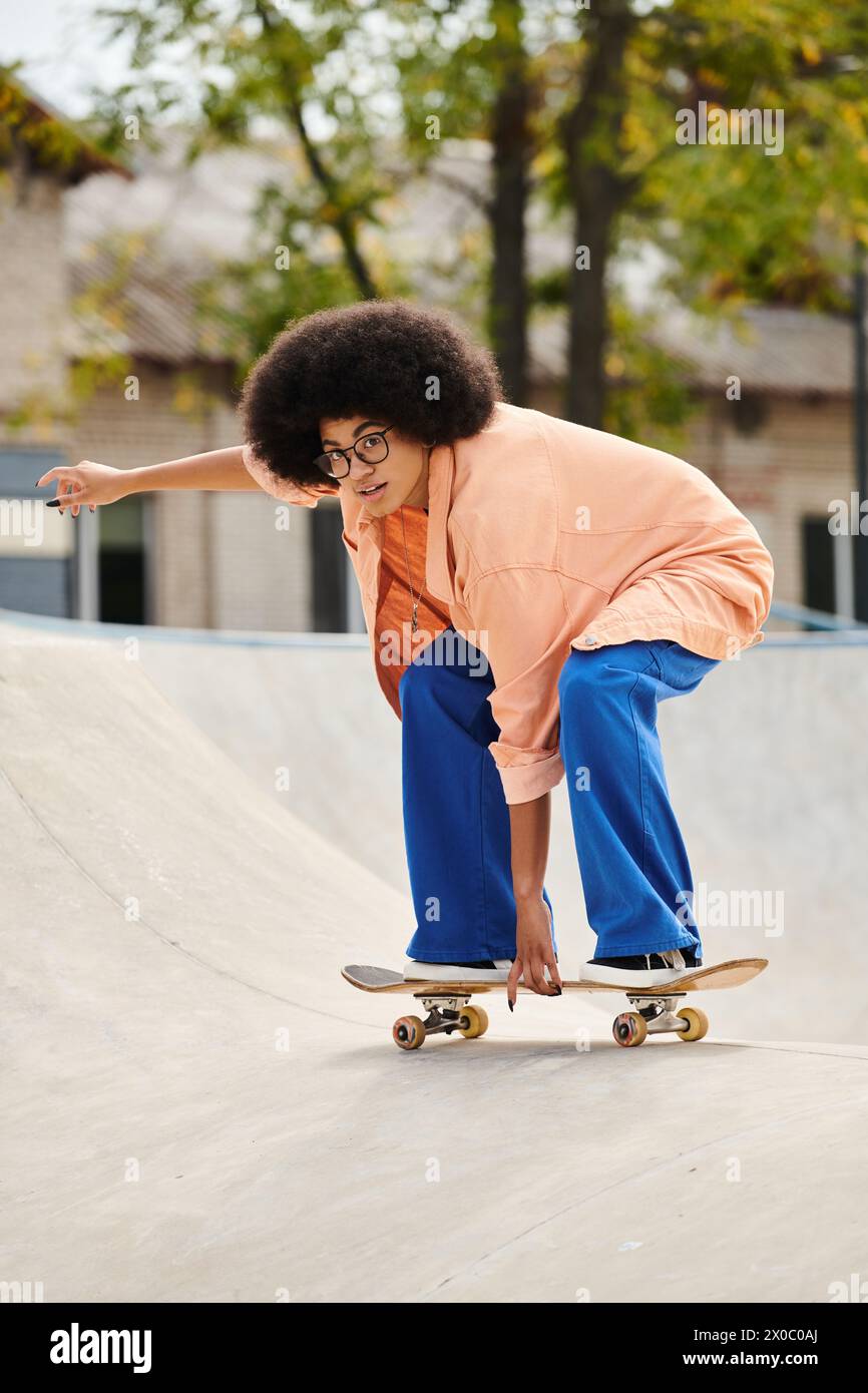 Curly-haired African American woman skateboarding on outdoor ramp in ...