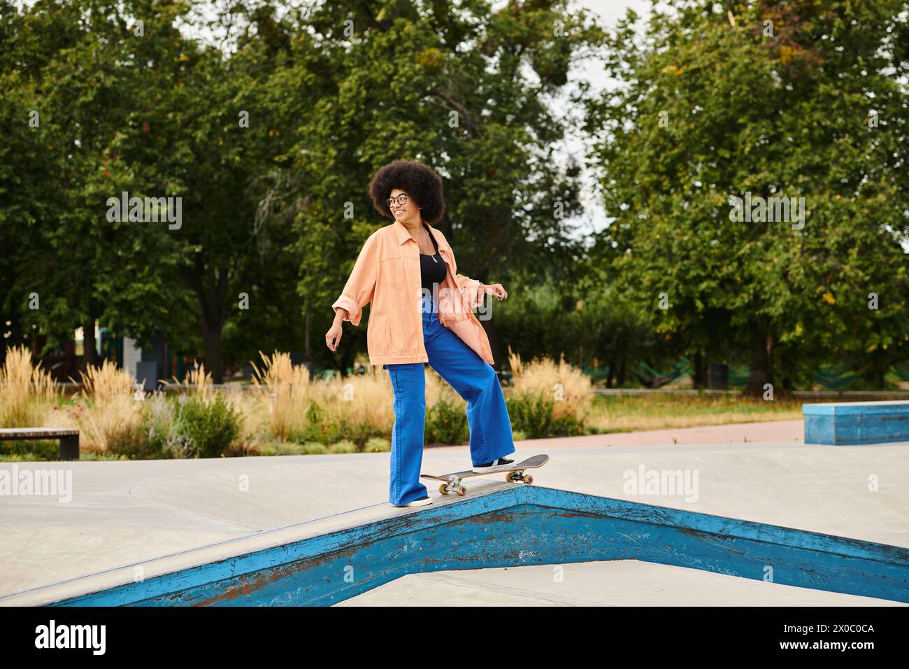 A young African American woman with curly hair rides a skateboard on a ...