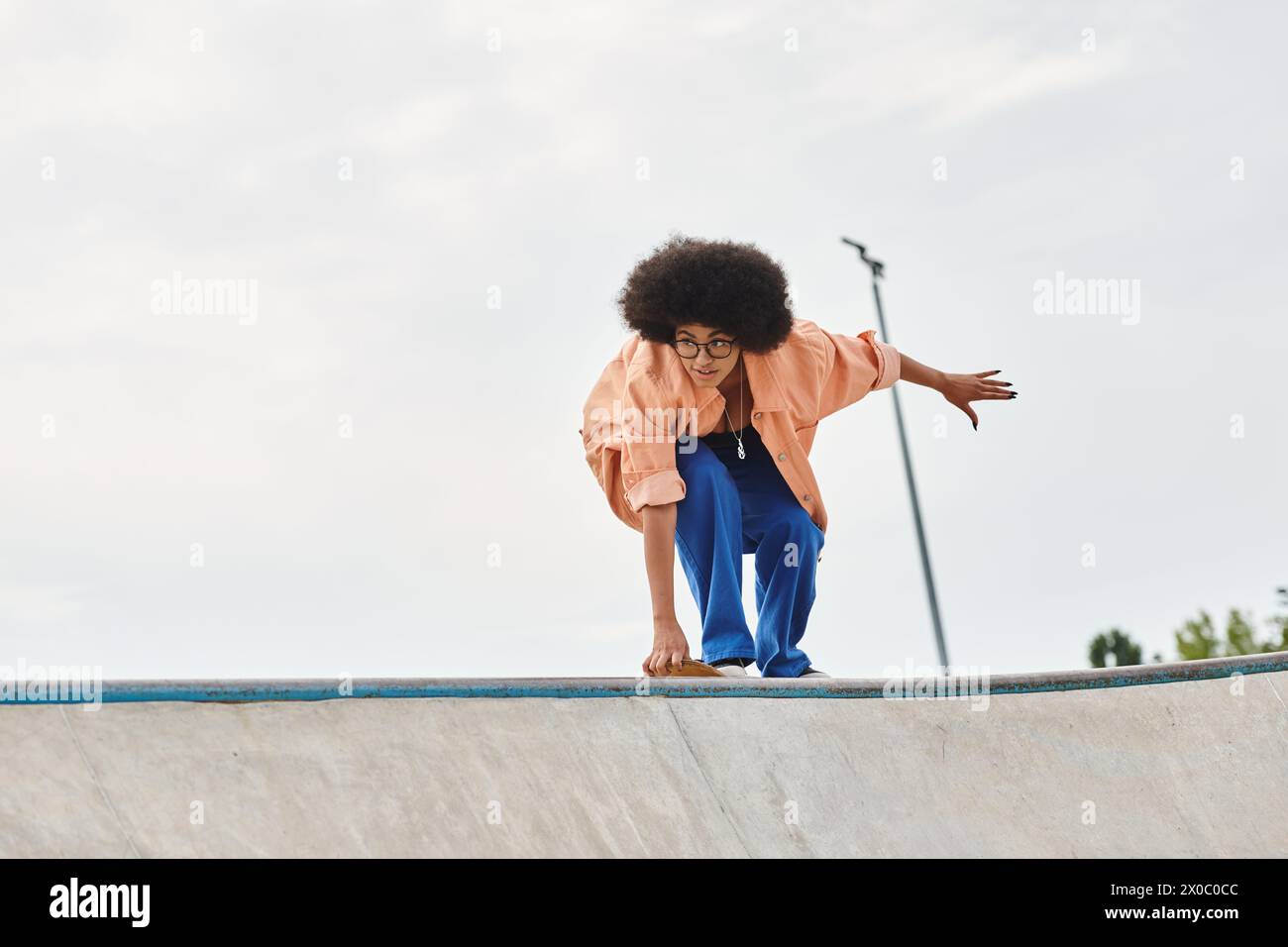 A young African American woman with curly hair riding a skateboard on a ...