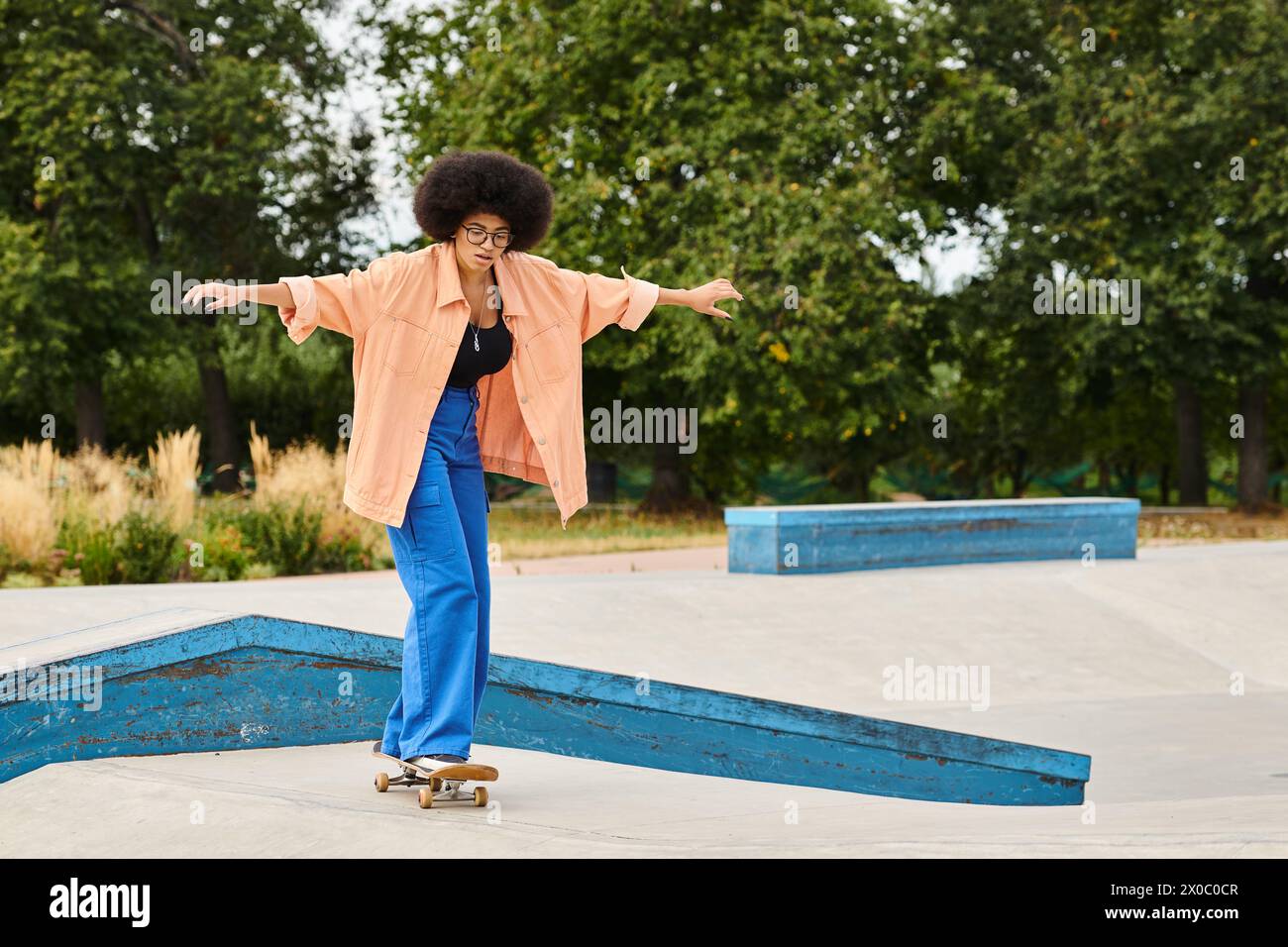 A young African American woman with curly hair rides a skateboard ...
