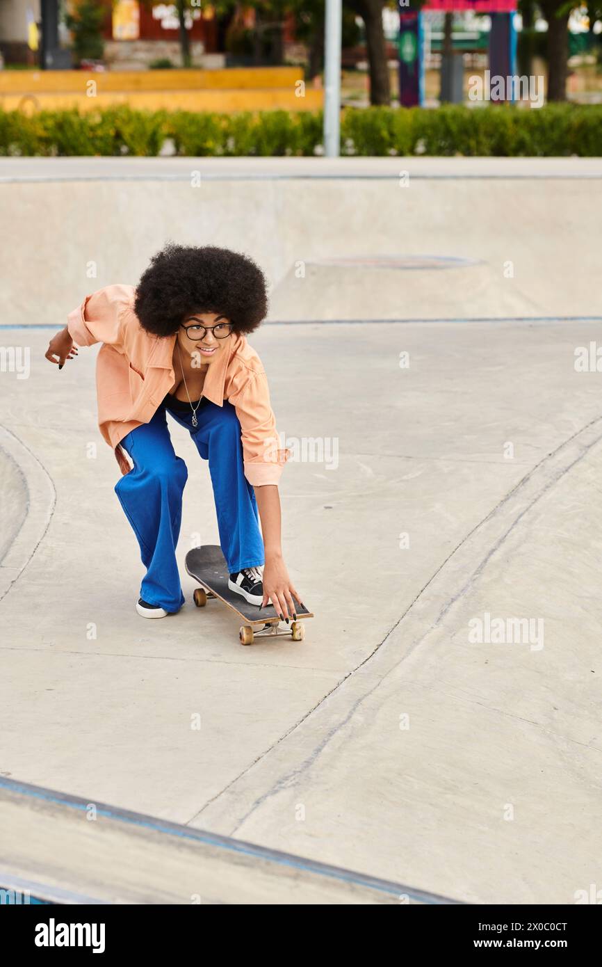 A young African American woman with curly hair skateboarding on a ramp ...