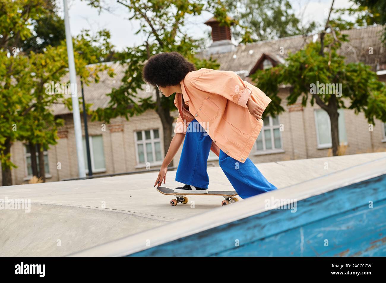 Young African American woman with curly hair skateboarding on a ramp at ...
