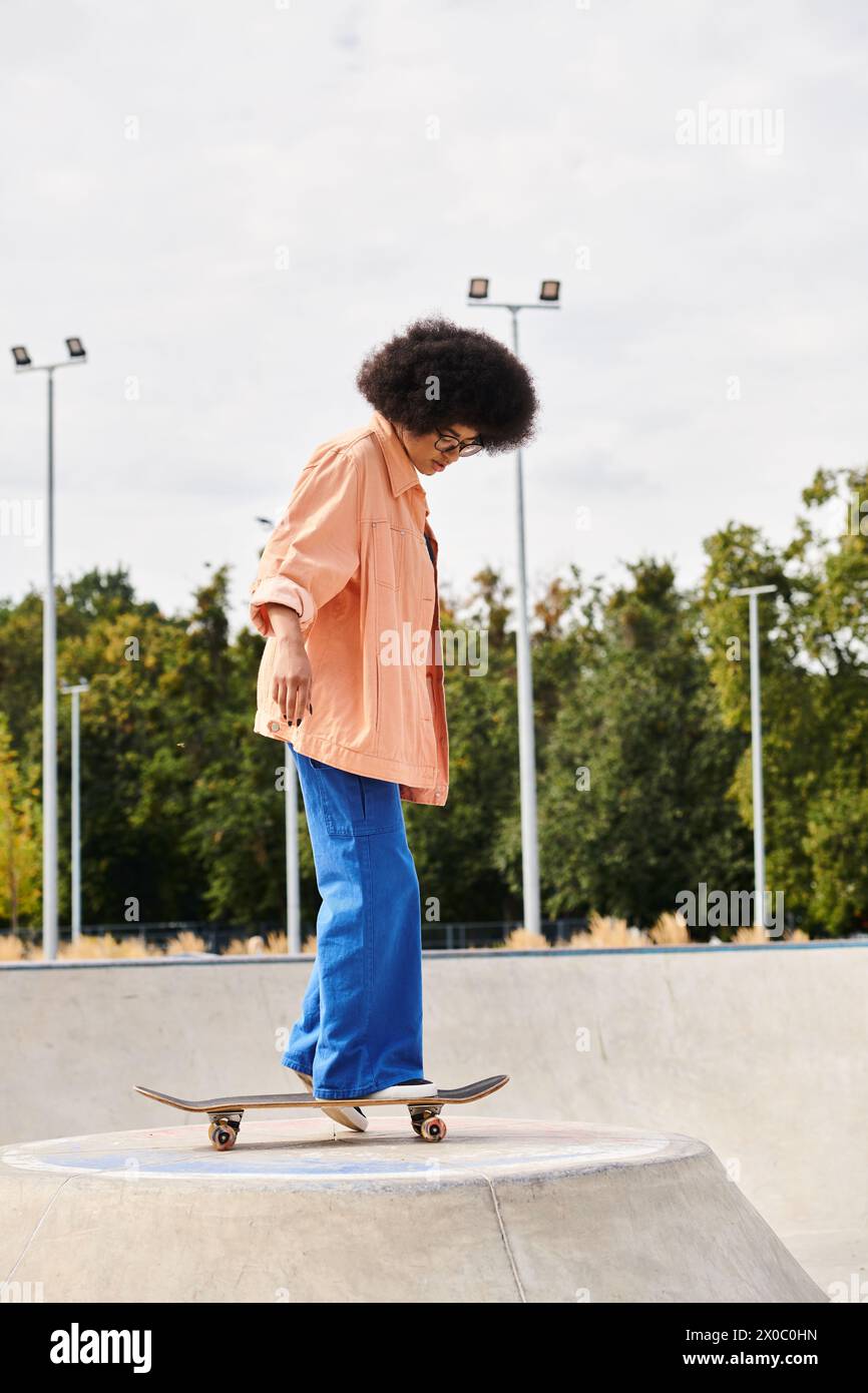 A young African American woman with curly hair skateboarding on a ramp ...
