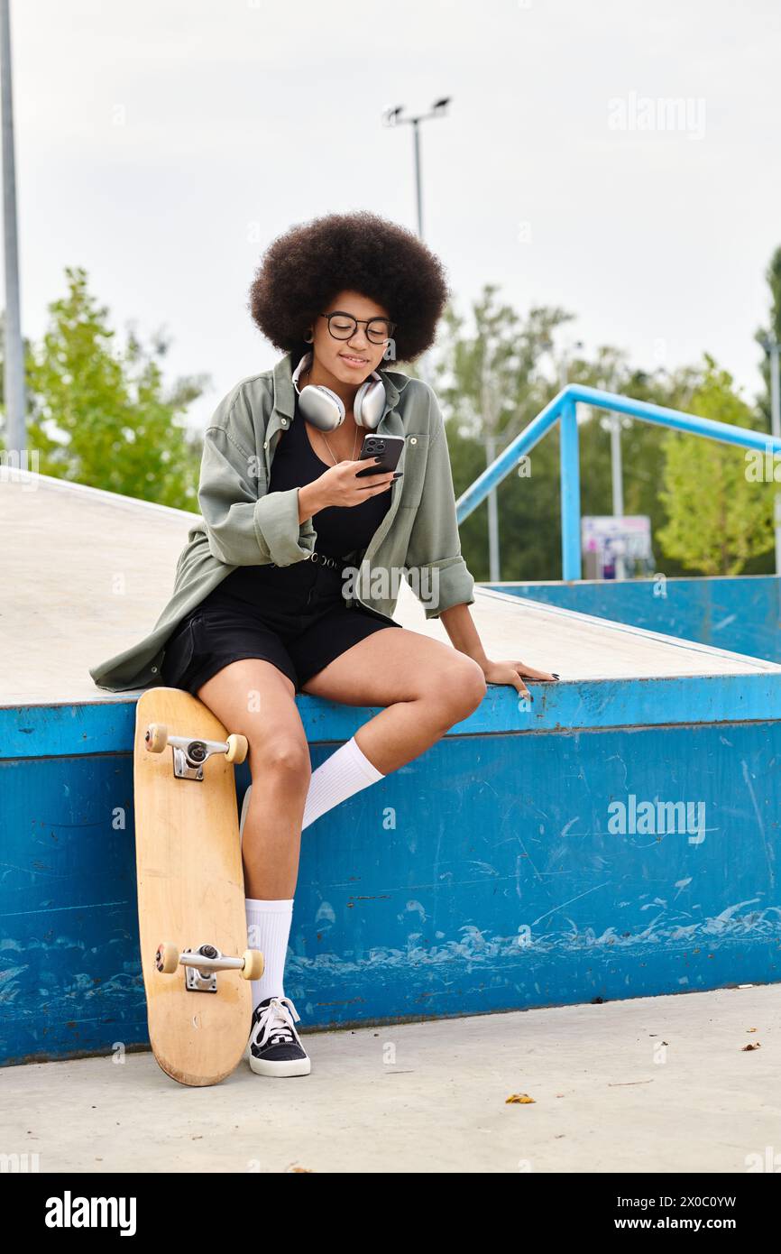 A young African American woman sits on her skateboard, poised next to a ...