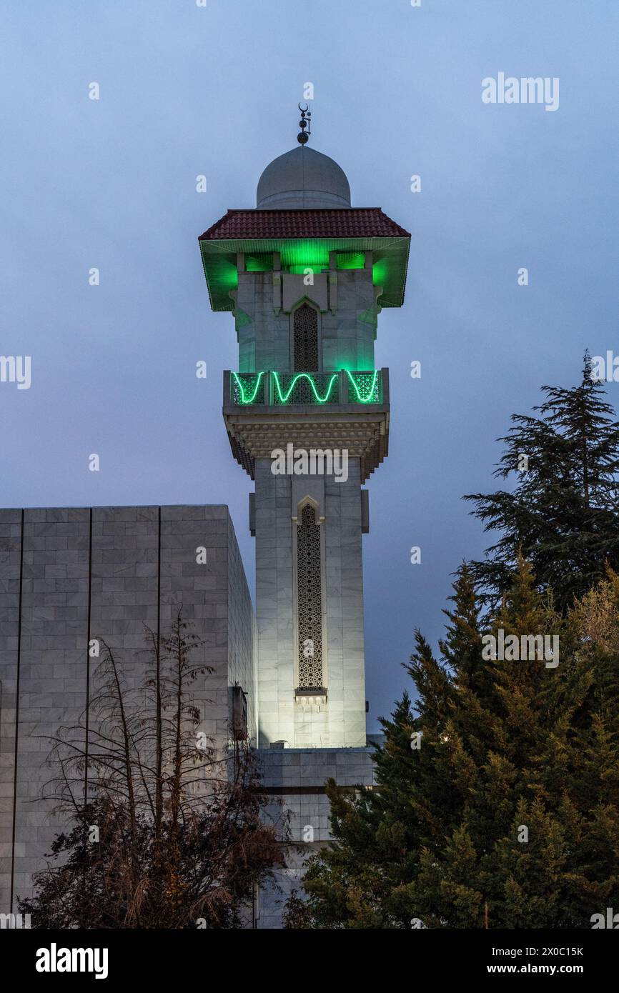 A majestic white mosque with a towering, illuminated minaret pierces ...
