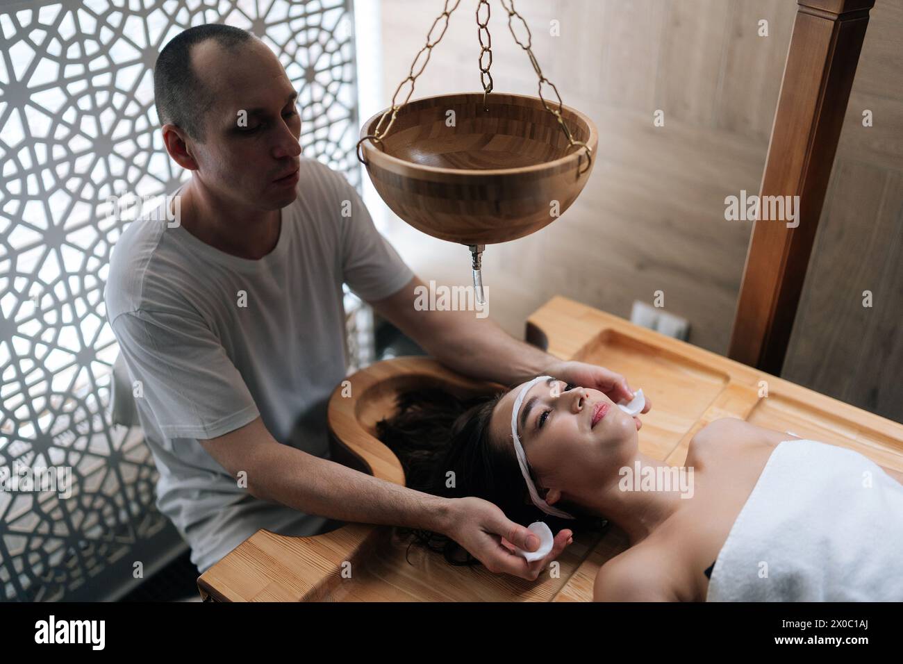 Portrait of spa master applying bandage to forehead of female client in ...