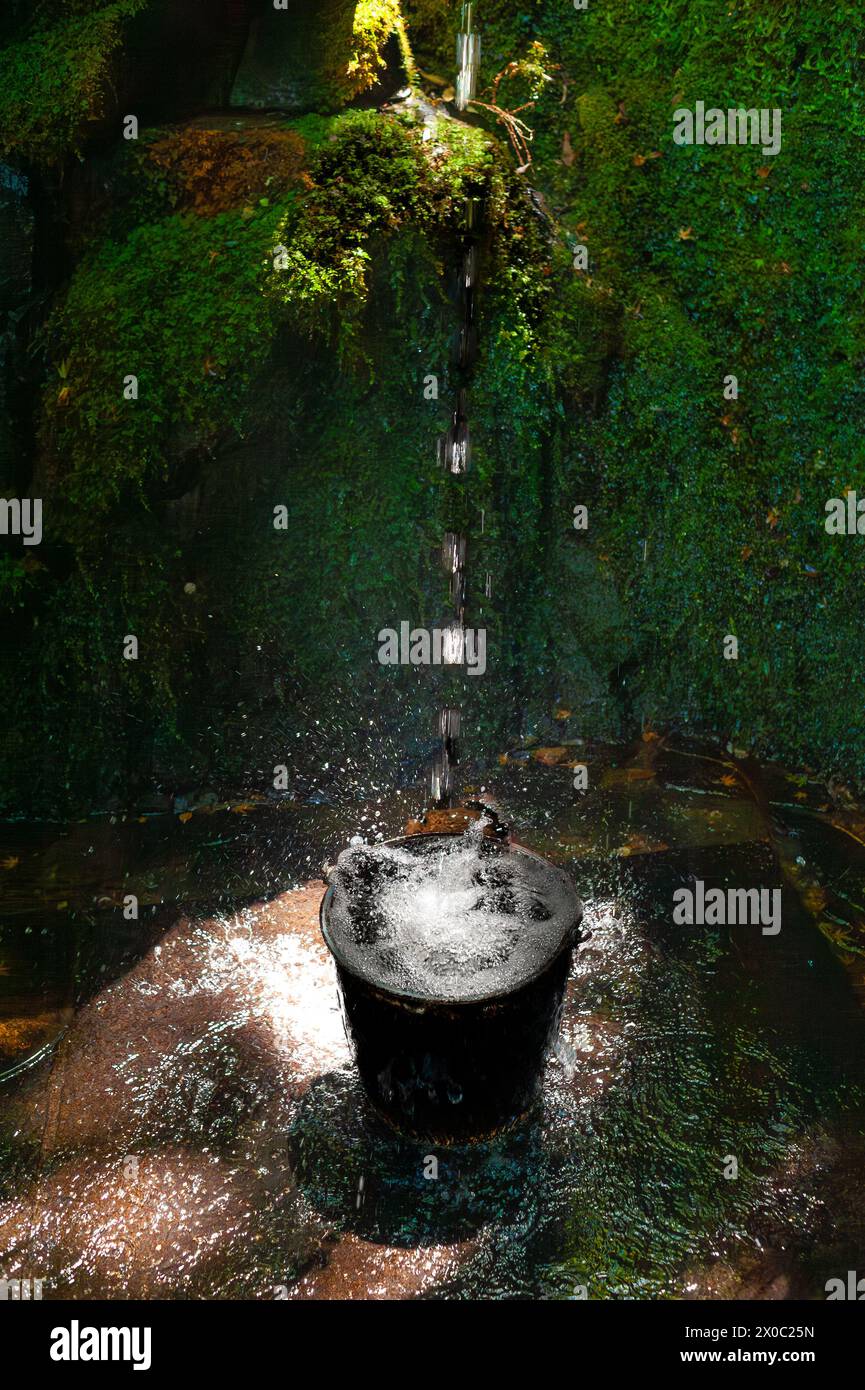 Waterfall dropping into a stone bucket in the gardens of Fushimi Inari ...