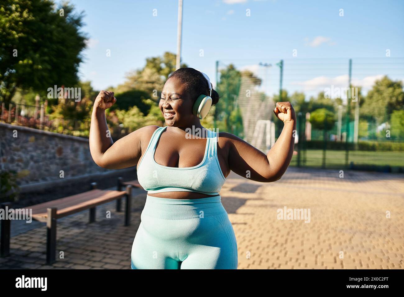 An African American woman in a sports bra and leggings flexes her ...