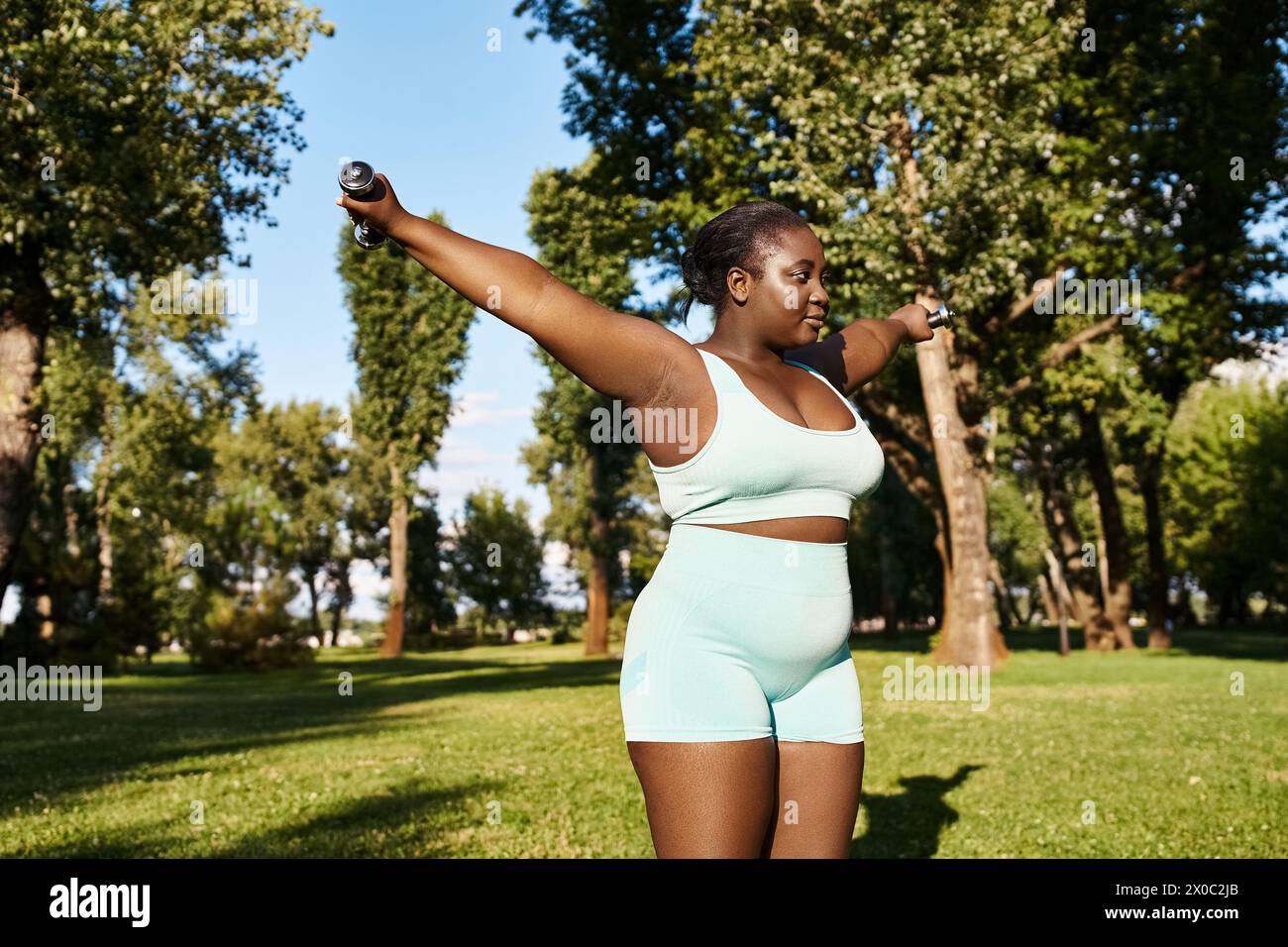 A curvy African American woman in blue sports bra and shorts holds a ...