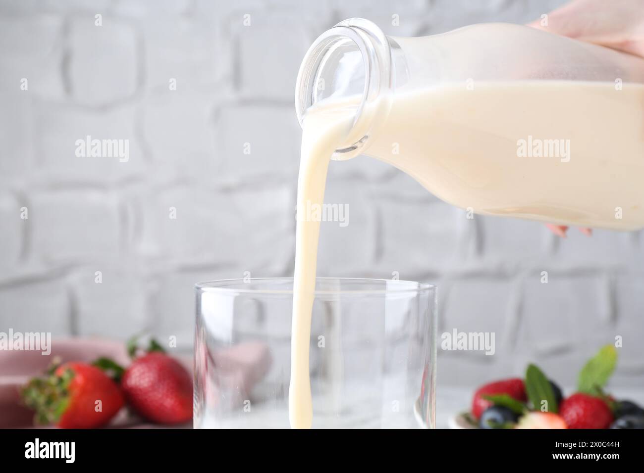 Woman pouring tasty yogurt into glass at table, closeup Stock Photo - Alamy