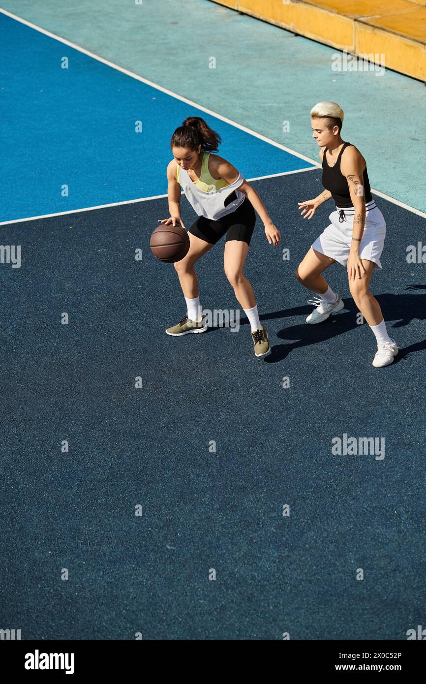 Two athletic young women stand triumphantly at the peak of a basketball ...