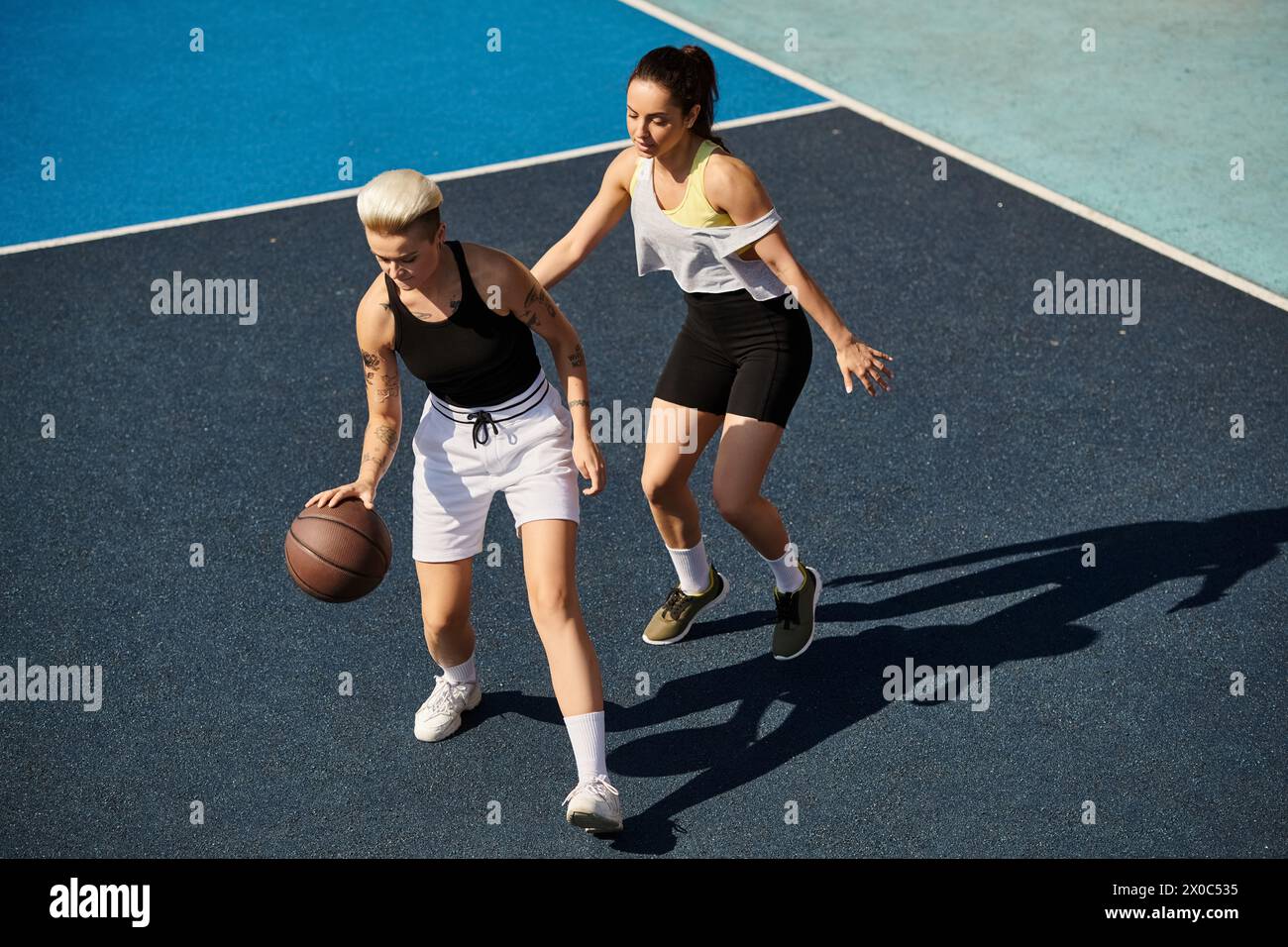 Two young women, friends, stand proudly on top of a basketball court ...