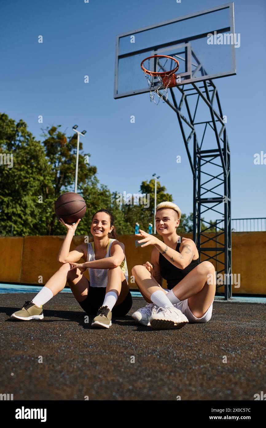 Two young women enjoy a game of basketball on the ground in the summer ...