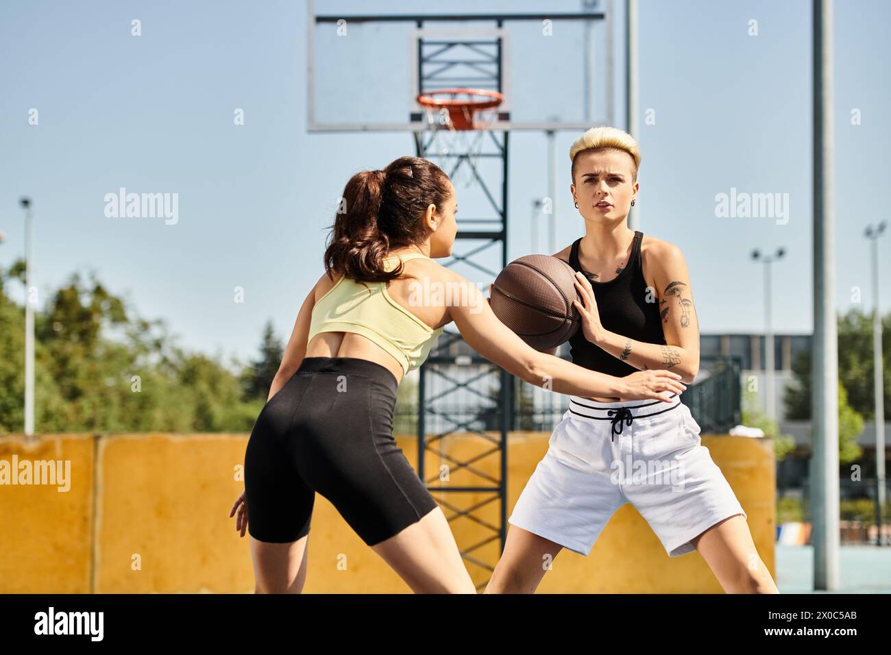 women engage in a friendly game of basketball on a sunny outdoor court ...