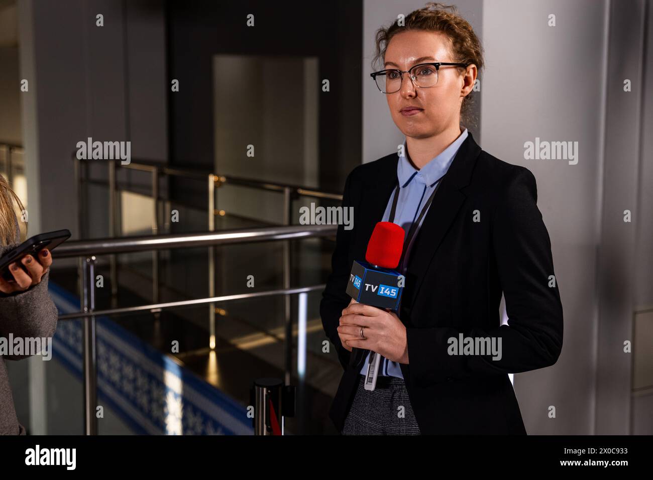 Female journalist with a microphone in her hand observes and prepares ...