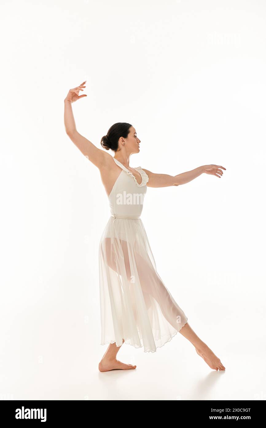 A graceful young woman in a flowing white dress expresses the beauty of ...