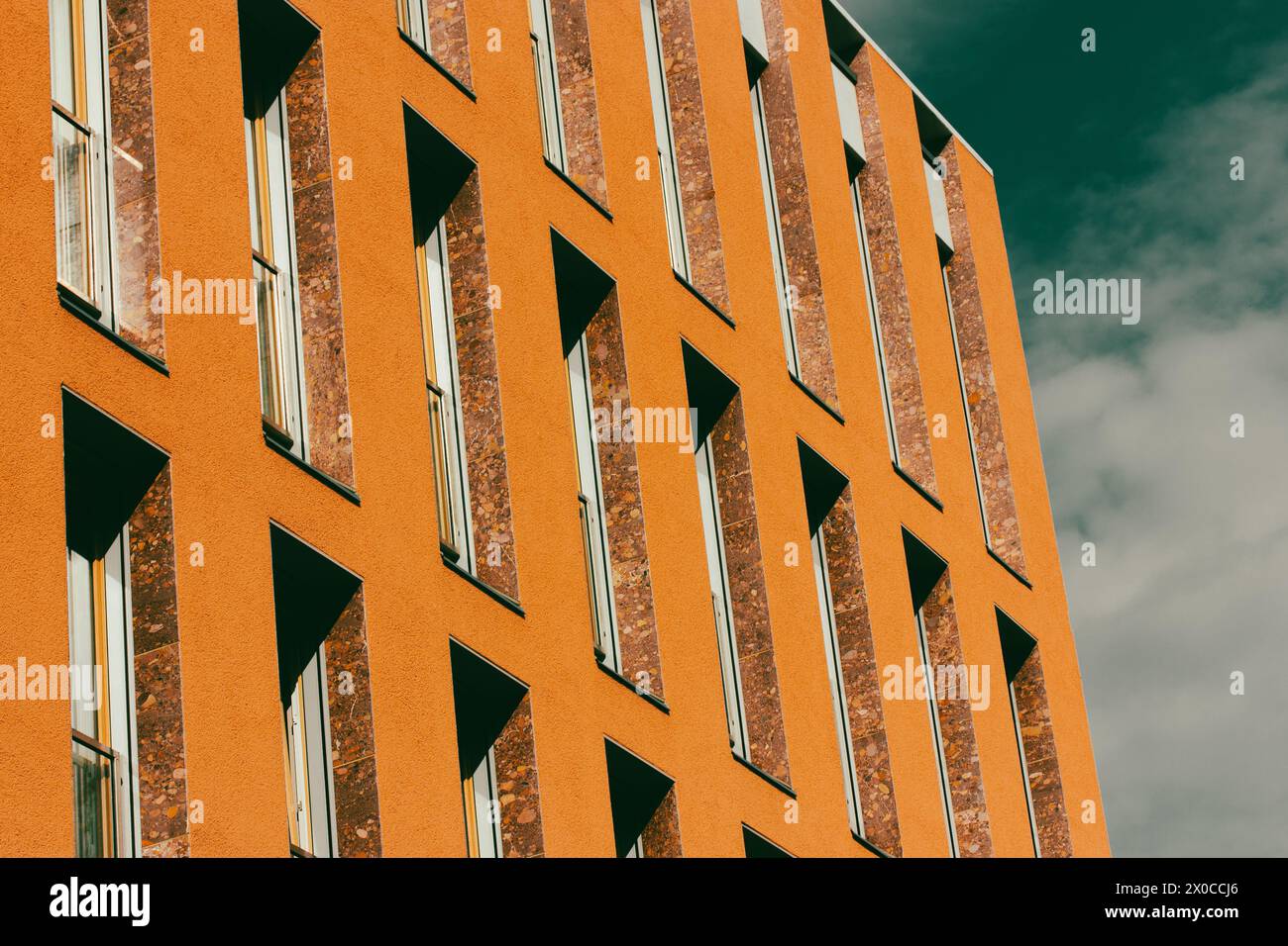 Fragment of an orange house facade with long narrow windows. High rise ...