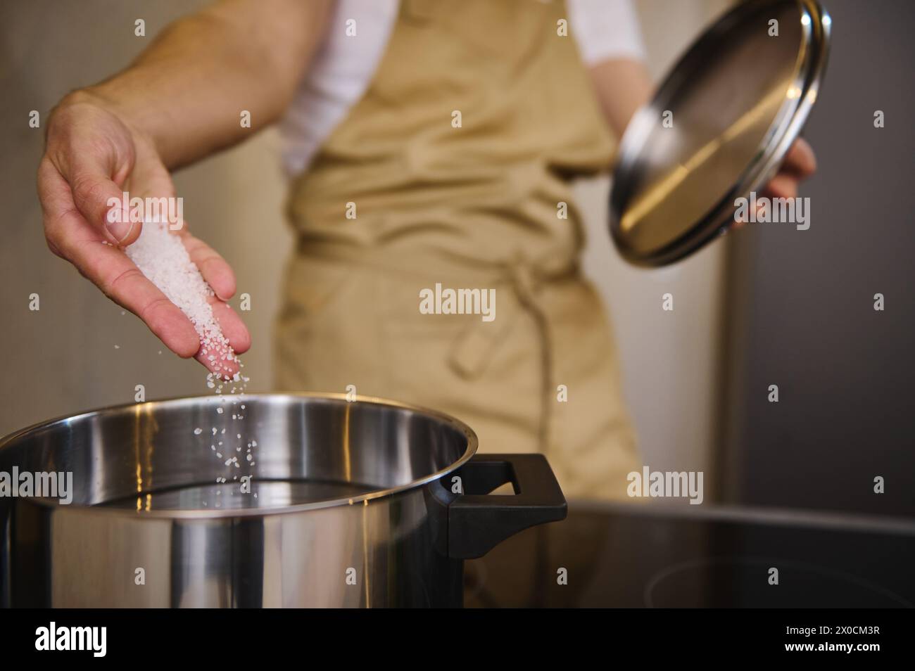 Close-up of unrecognizable chef adding salt into a boiling water in the ...
