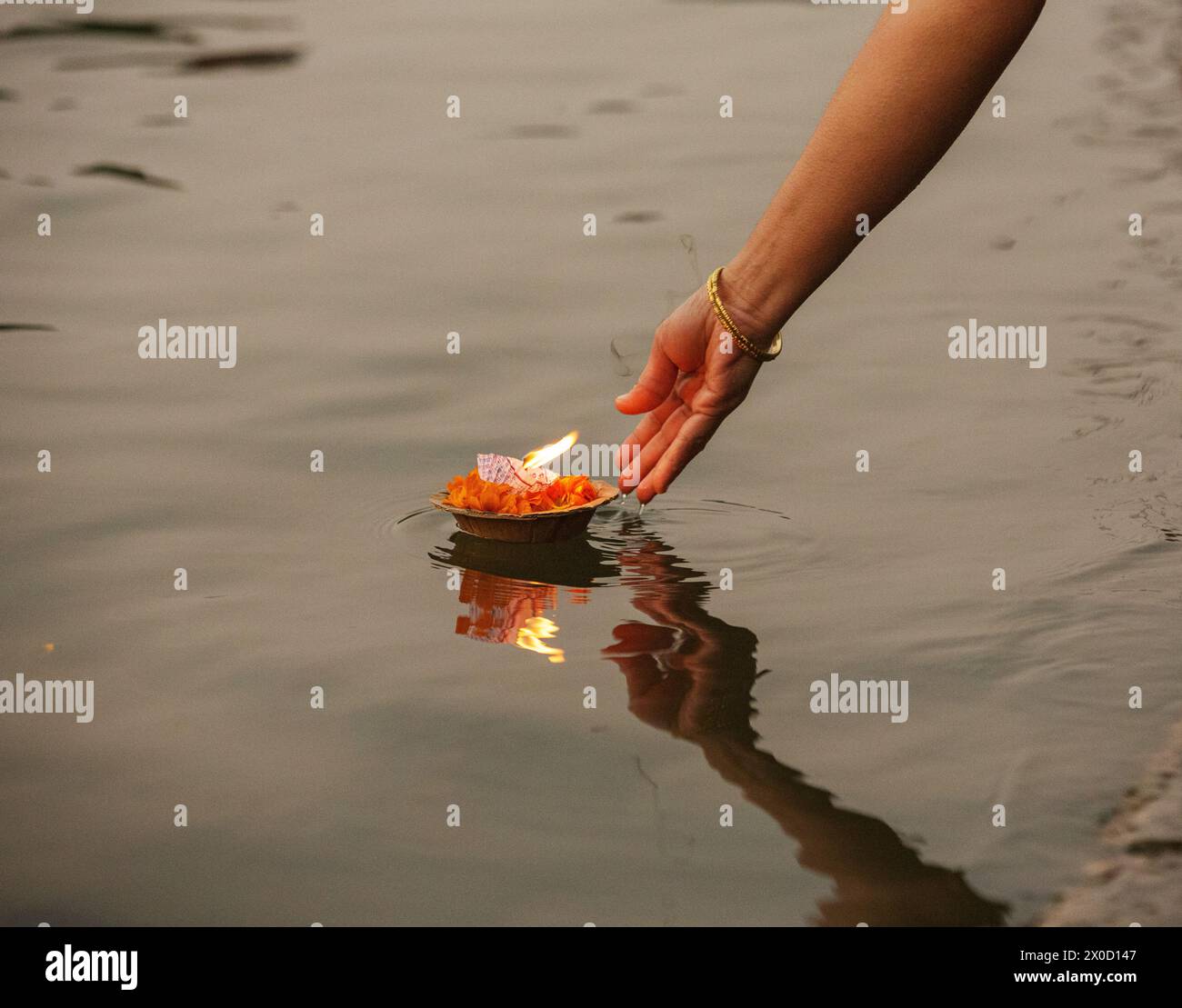 Pilgrim releasing a floating candle into the Ganges River at Varanasi ...