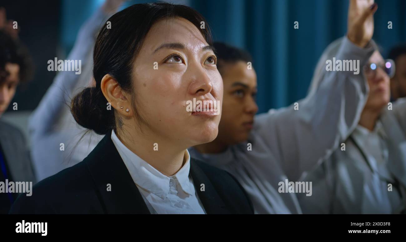 Portrait of Asian female journalist raising hand to ask question ...