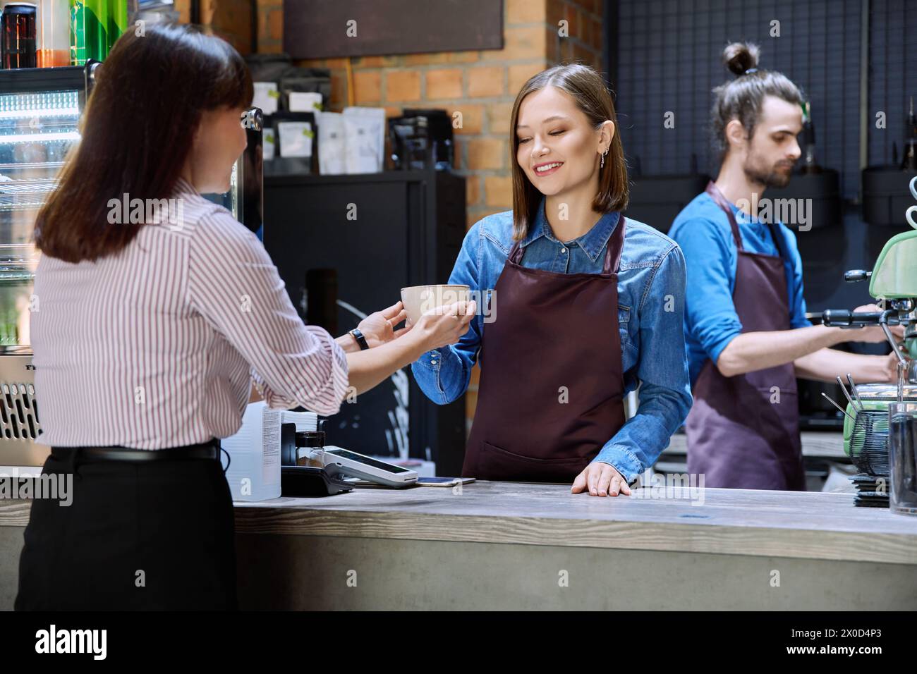 Woman customer of coffee shop near counter with cup of coffee talking ...