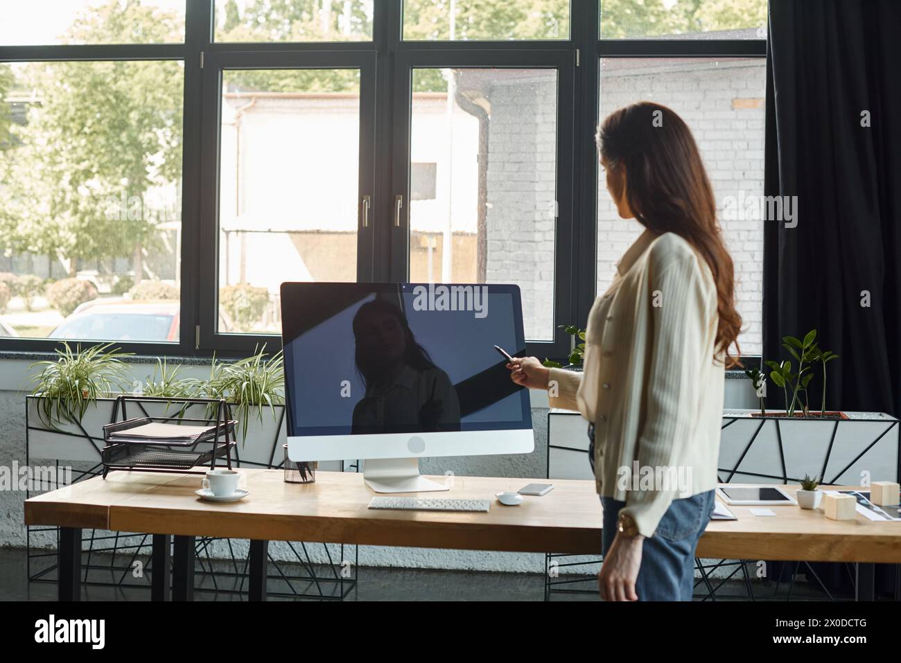 A businesswoman stands confidently in front of a computer screen in a ...