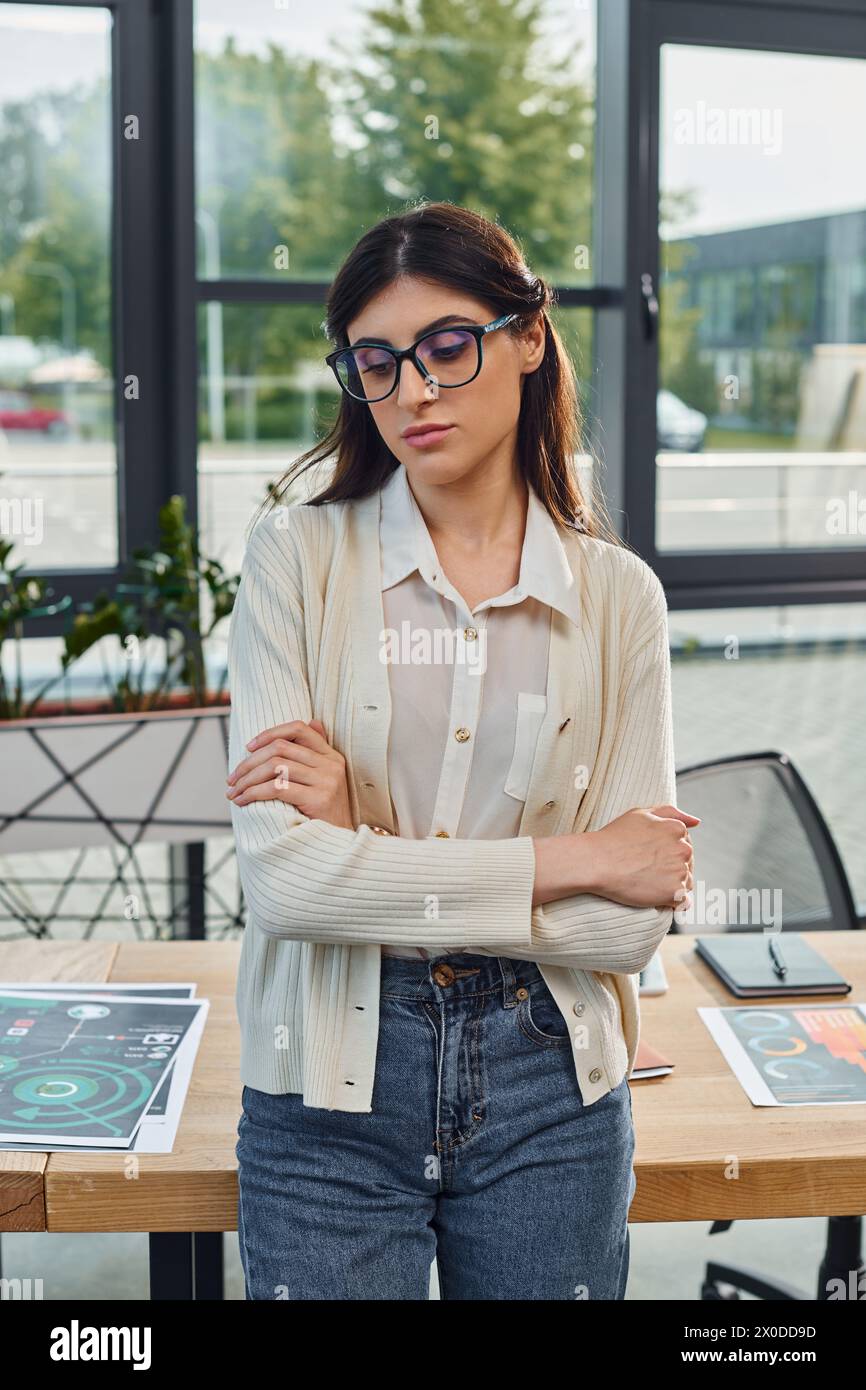 A stylish woman with glasses stands confidently by a table in a modern ...