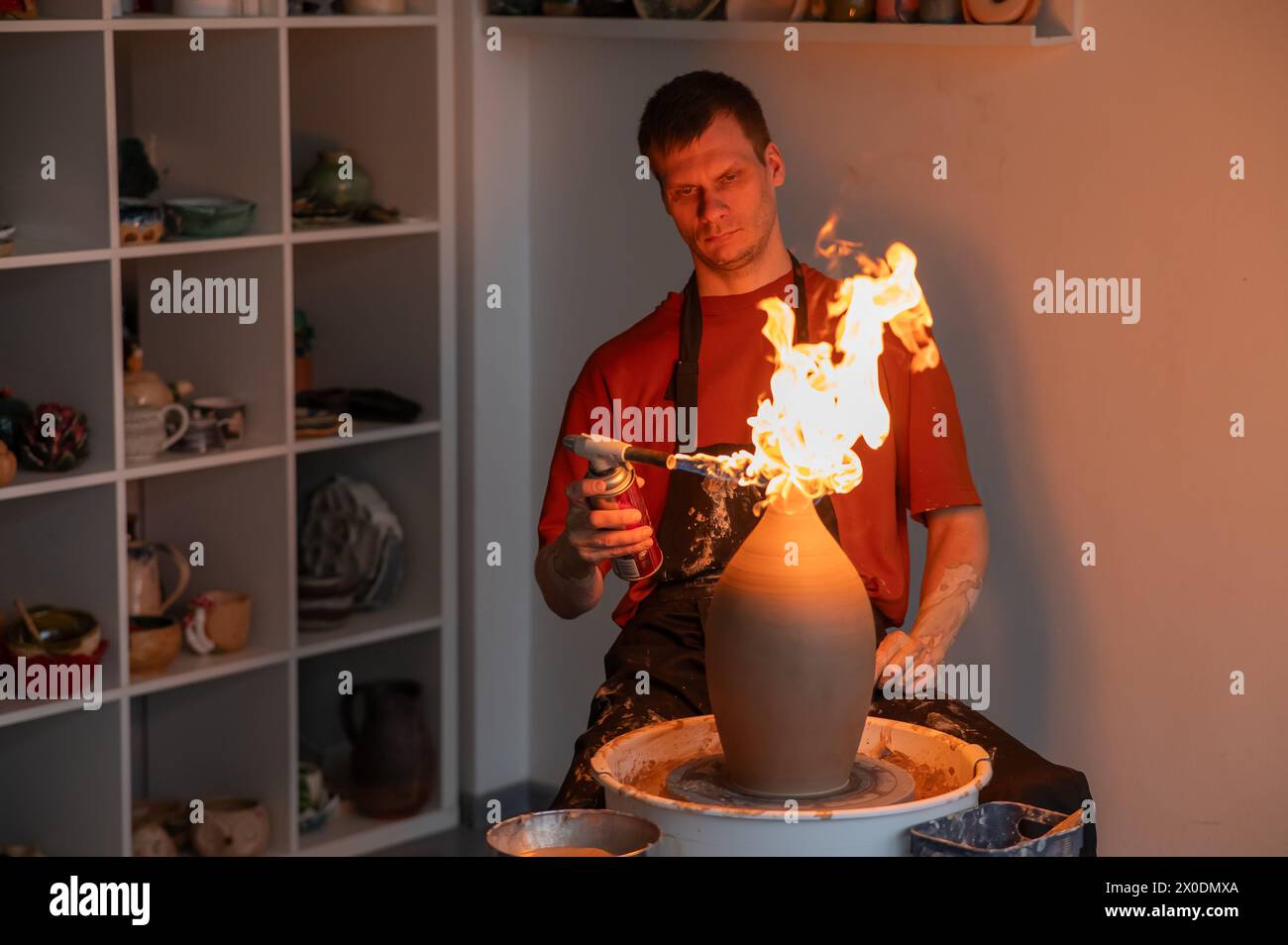 A potter burns a jug with a gas burner on a potter's wheel Stock Photo ...