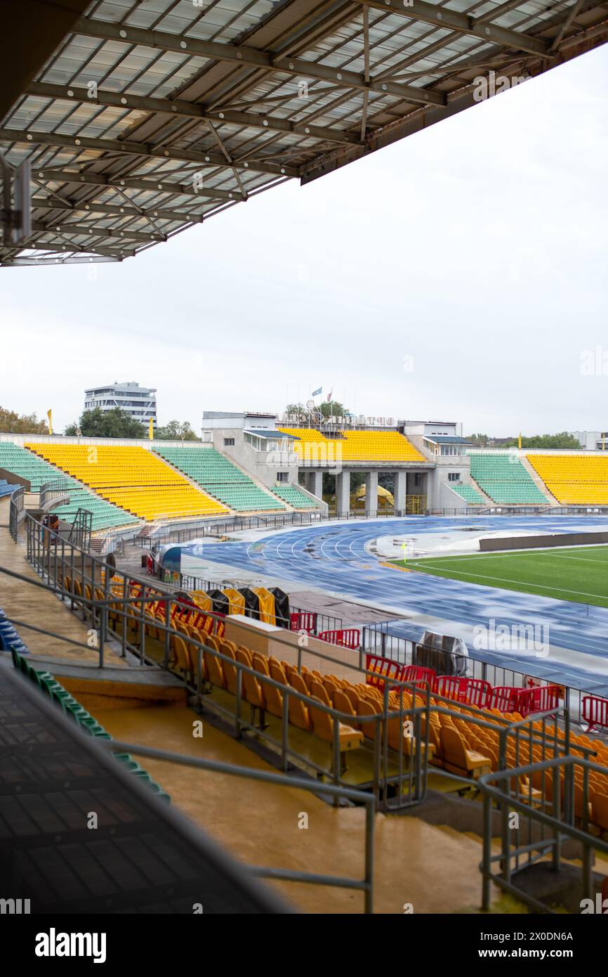 Rows of bright yellow stadium seats with blue track. Old stadium in ...