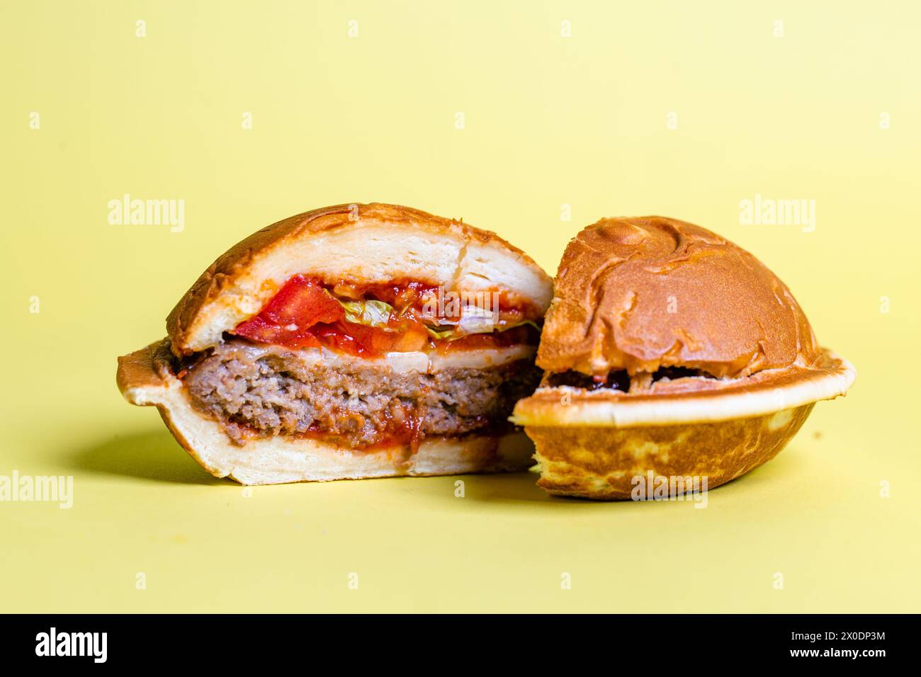 juicy burger cut with delicious filling on a yellow background Stock ...