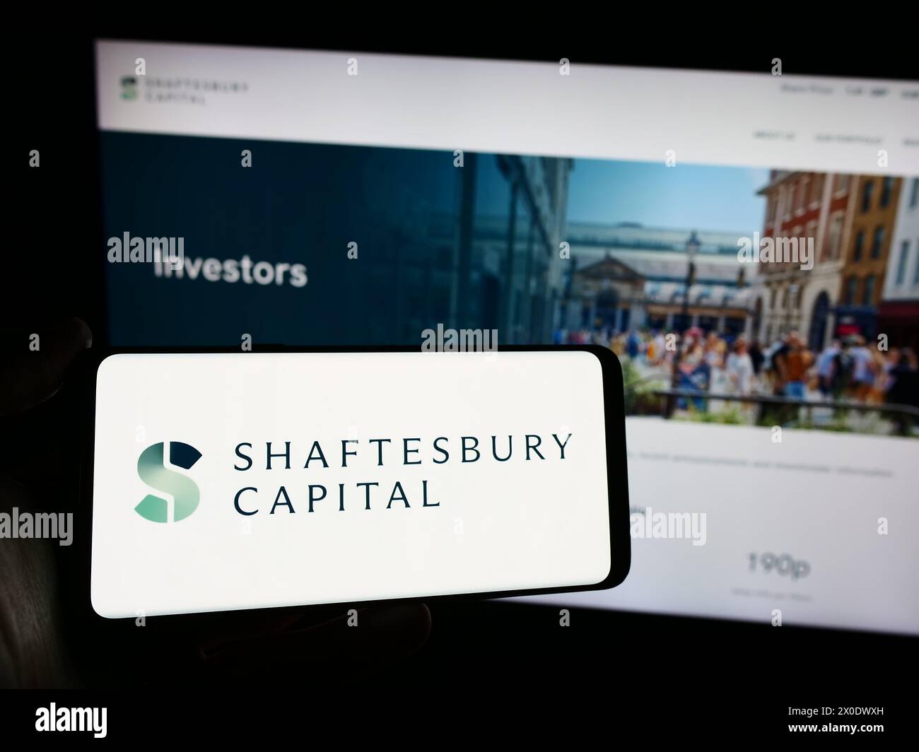 Person holding mobile phone with logo of British investment company ...