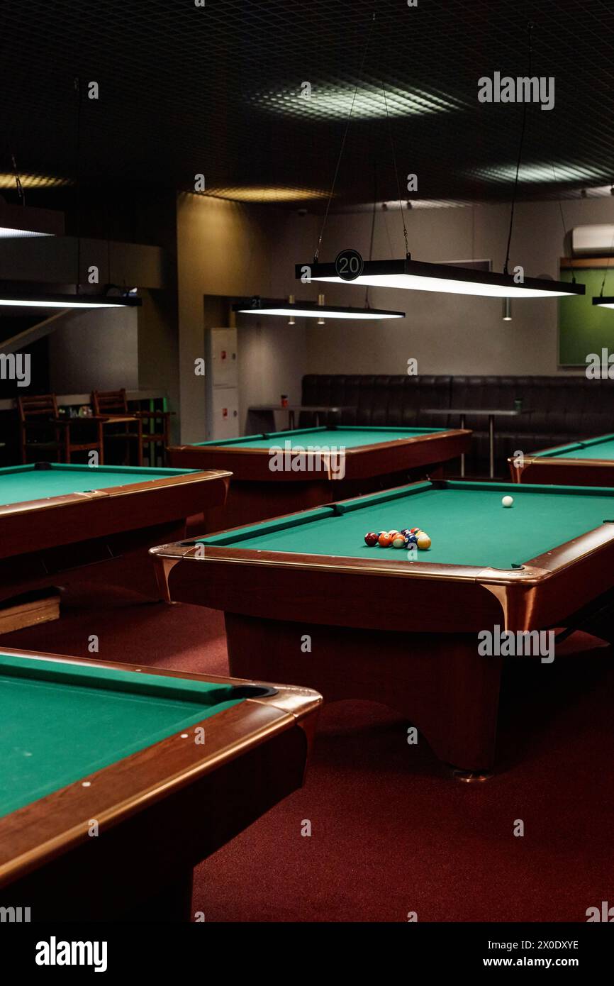 Vertical background image of low lit pool club with several billiard ...
