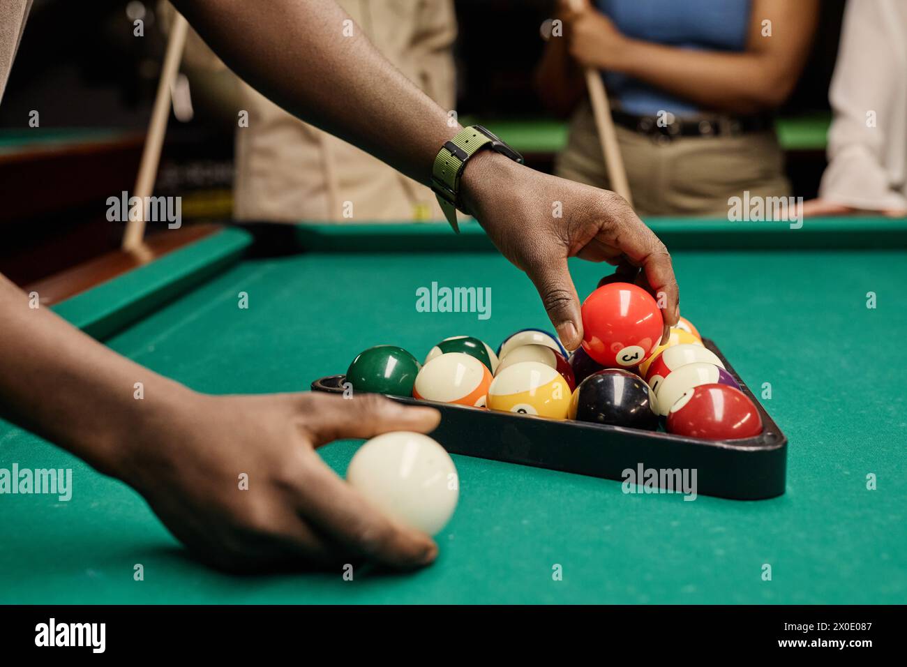 Side view closeup of hands putting billiard balls in triangle frame for ...