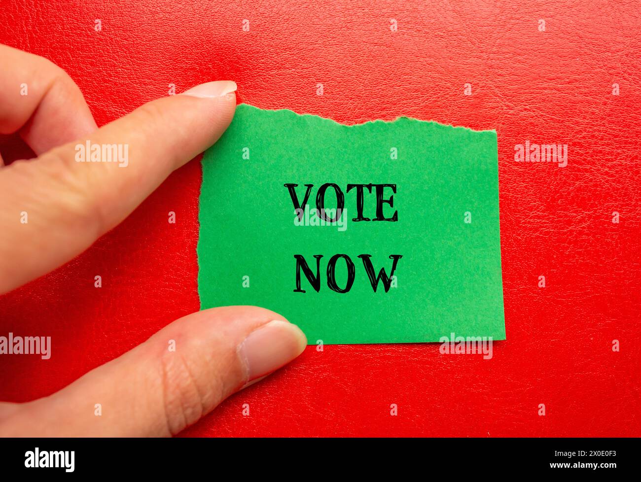Vote now words written on ripped green paper with red background ...